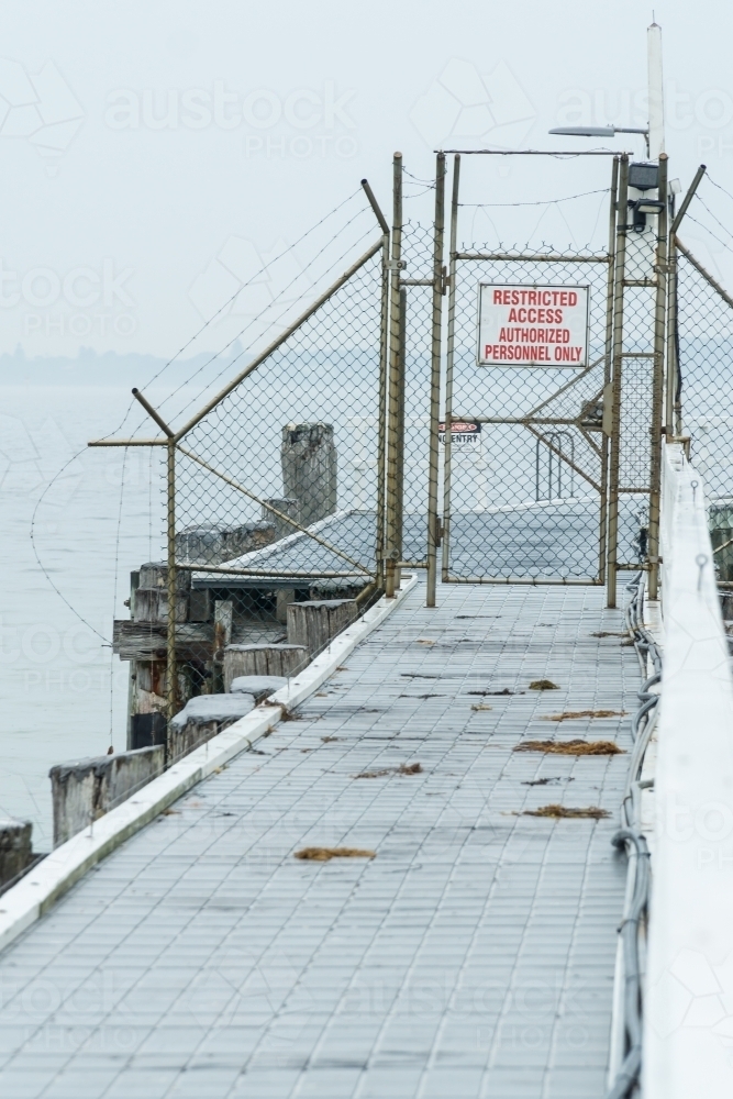 Image of Looking along a seaside jetty to a locked gate and exclusion ...