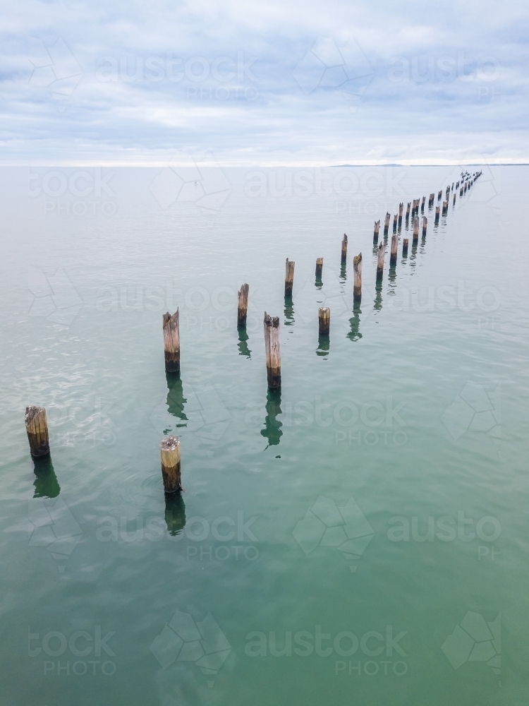 Image of Looking down on a row of old jetty pylons disappearing toward ...