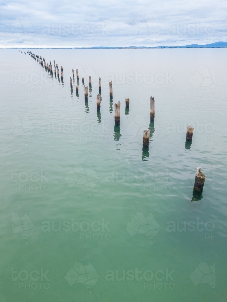 Image of Looking down on a row of old jetty pylons disappearing toward ...