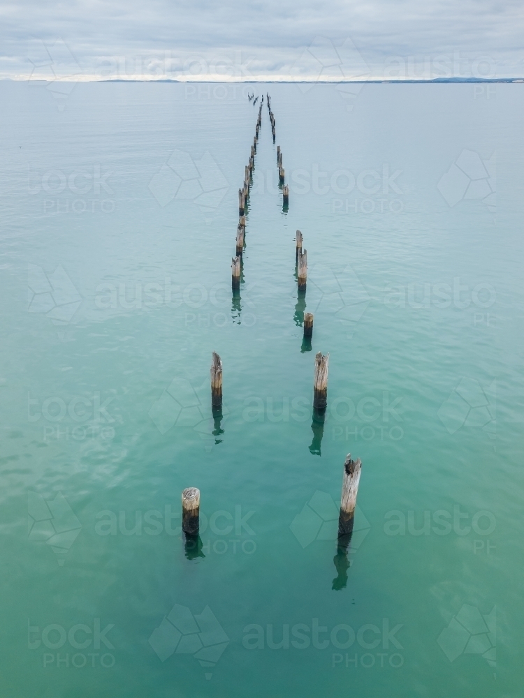 Image of Looking down on a row of old jetty pylons disappearing toward ...