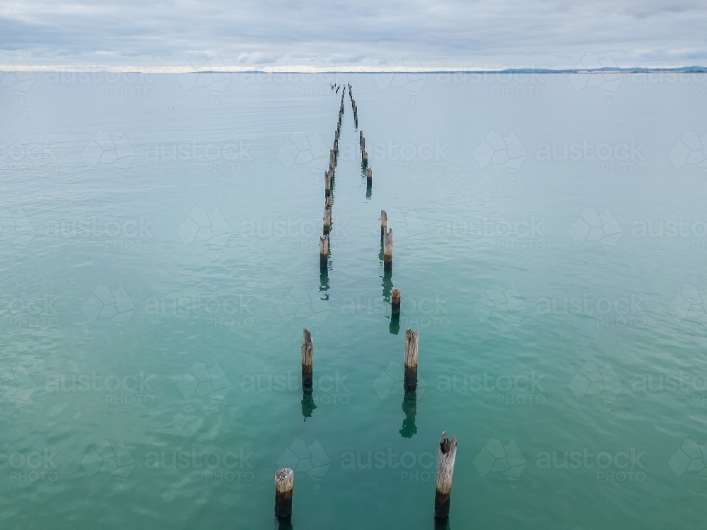 Image of Looking down on a row of old jetty pylons disappearing toward ...