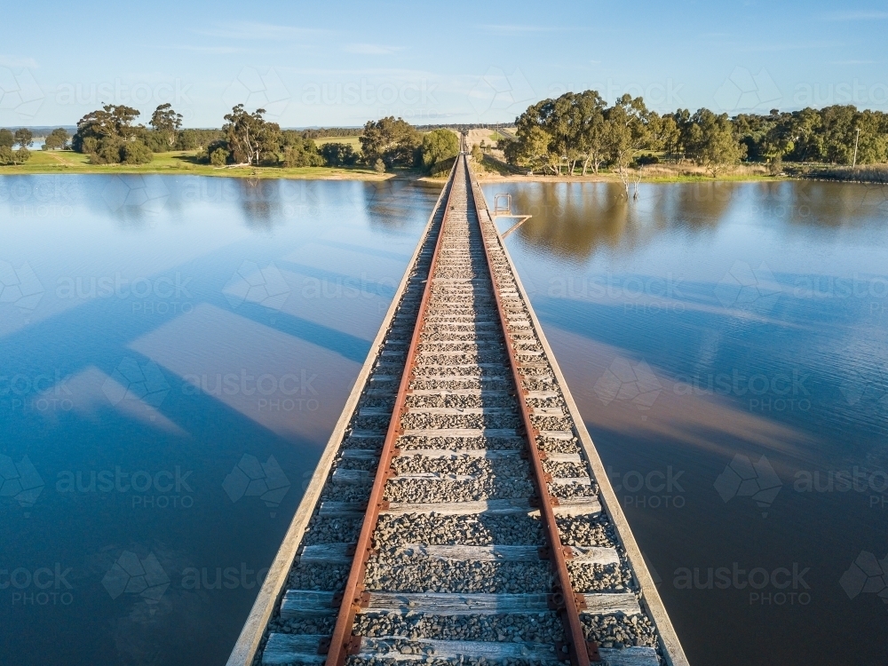 Image of Looking down railway tracks on top of a bridge across a lake ...