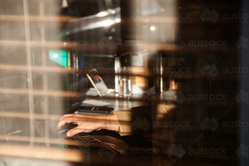 Image of Looking through window at person in home office using computer ...