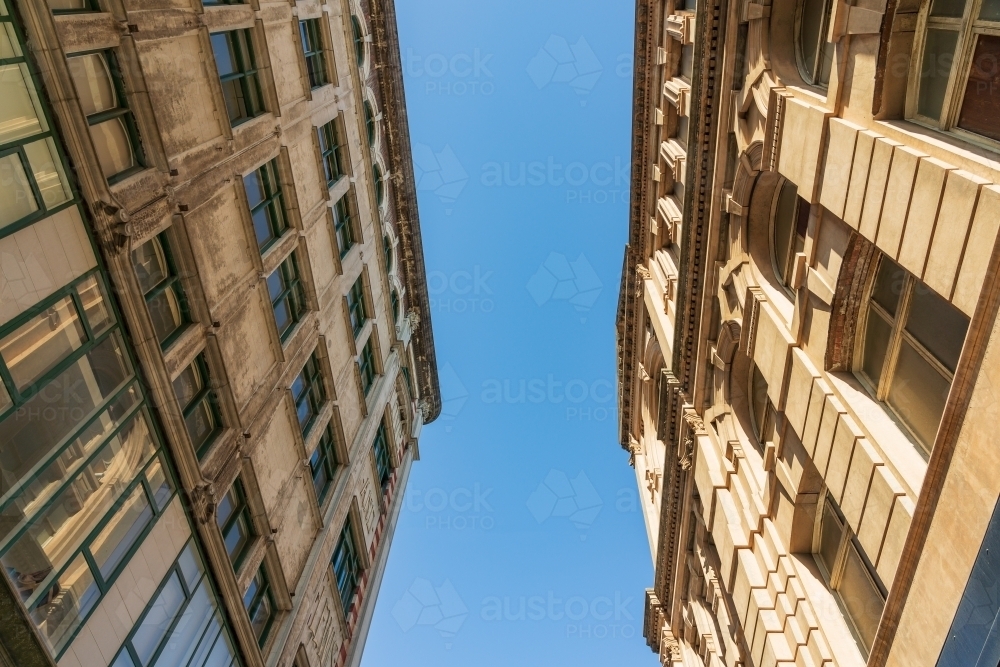 Image of Looking up a blue sky between two historic building facades ...