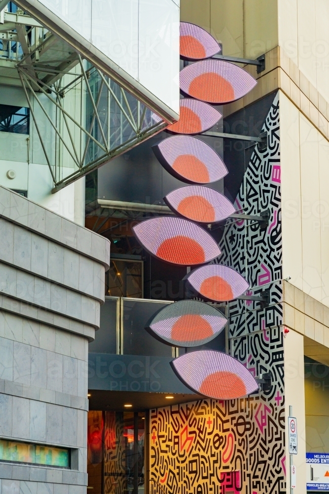 Image of Looking up at a display of lights shaped like eyes on the side ...