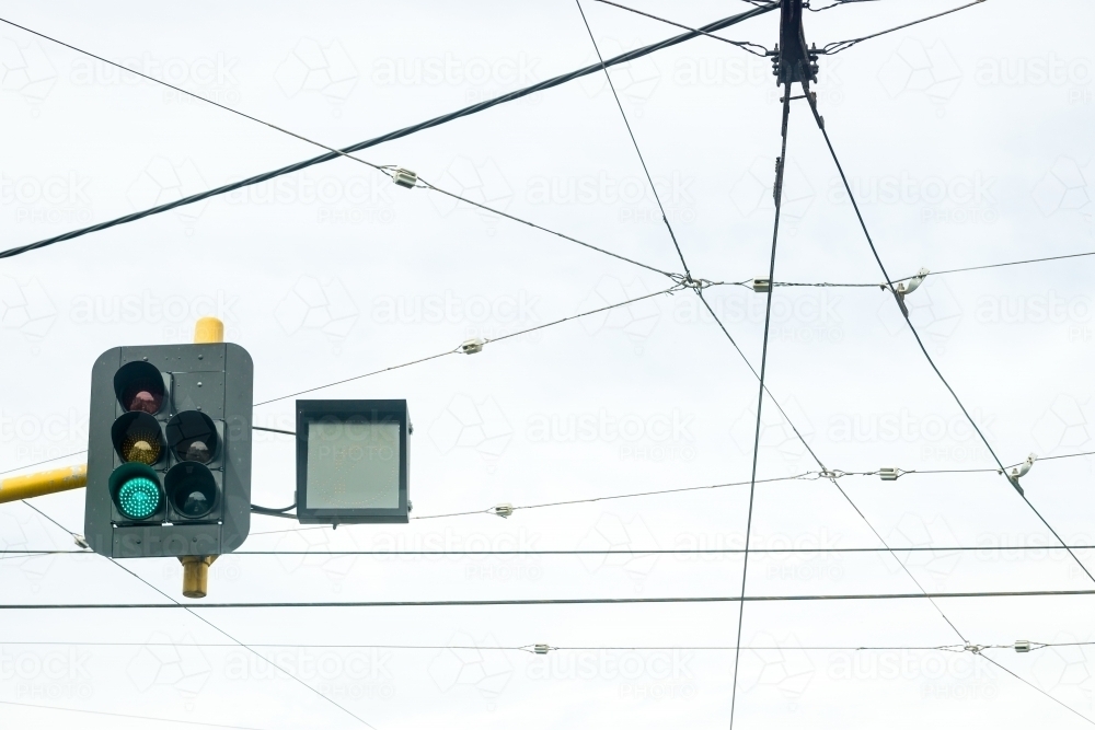 Image of Looking up at a set of traffic lights amongst overhead tram ...