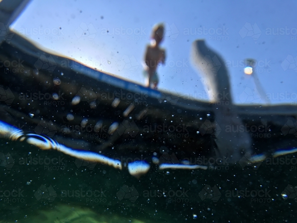 Image of Looking up from underwater at boy standing on jetty - Austockphoto