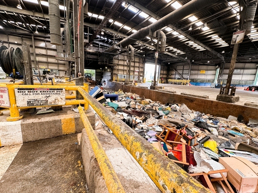 Image of lots of rubbish inside a waste management facility - Austockphoto