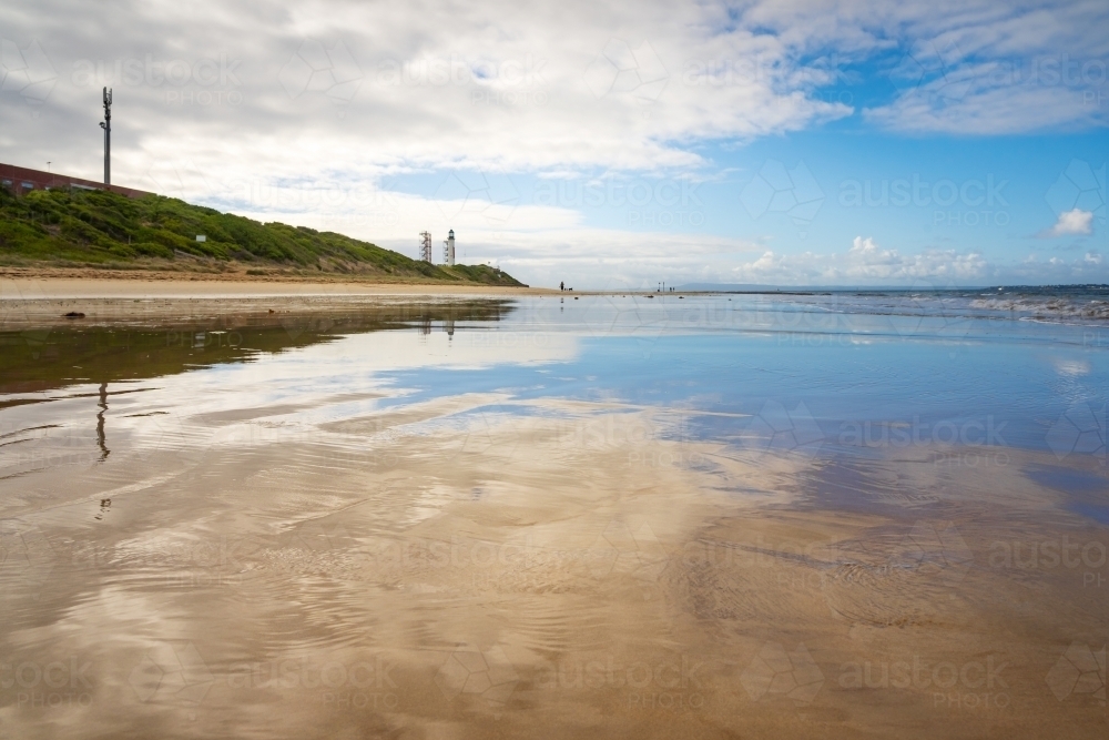Image of Low angled view along a beach with reflections of a lighthouse ...