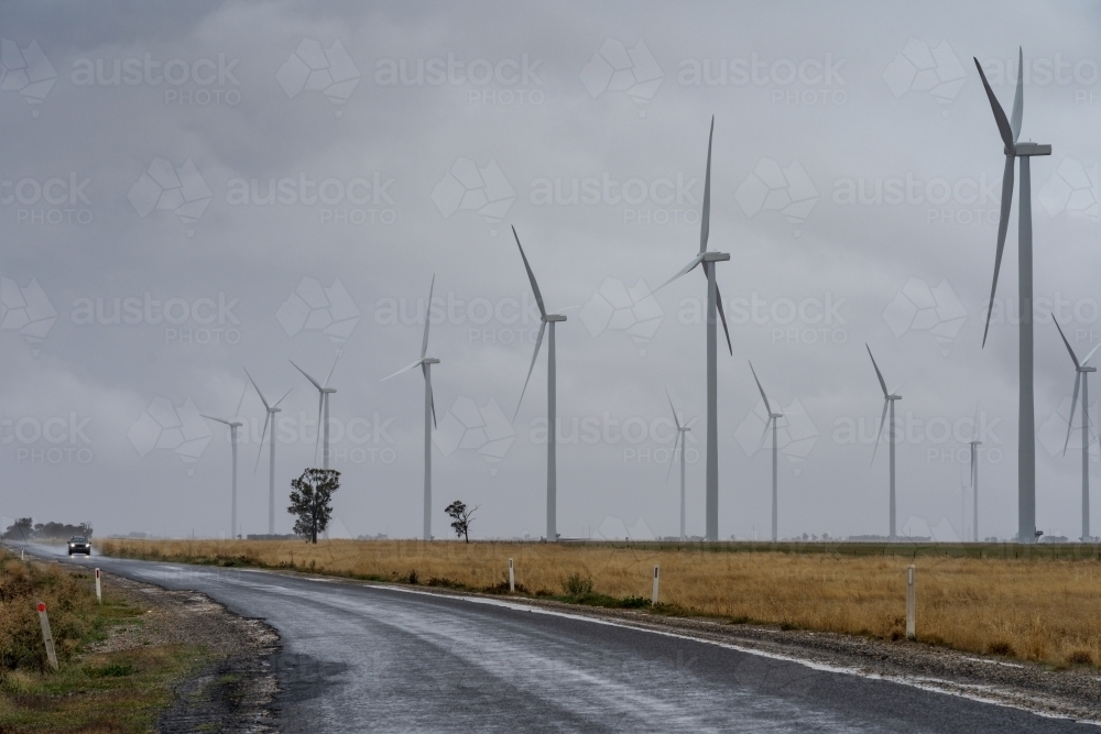 Image of Low angled view of a rural road and cluster of wind turbines ...