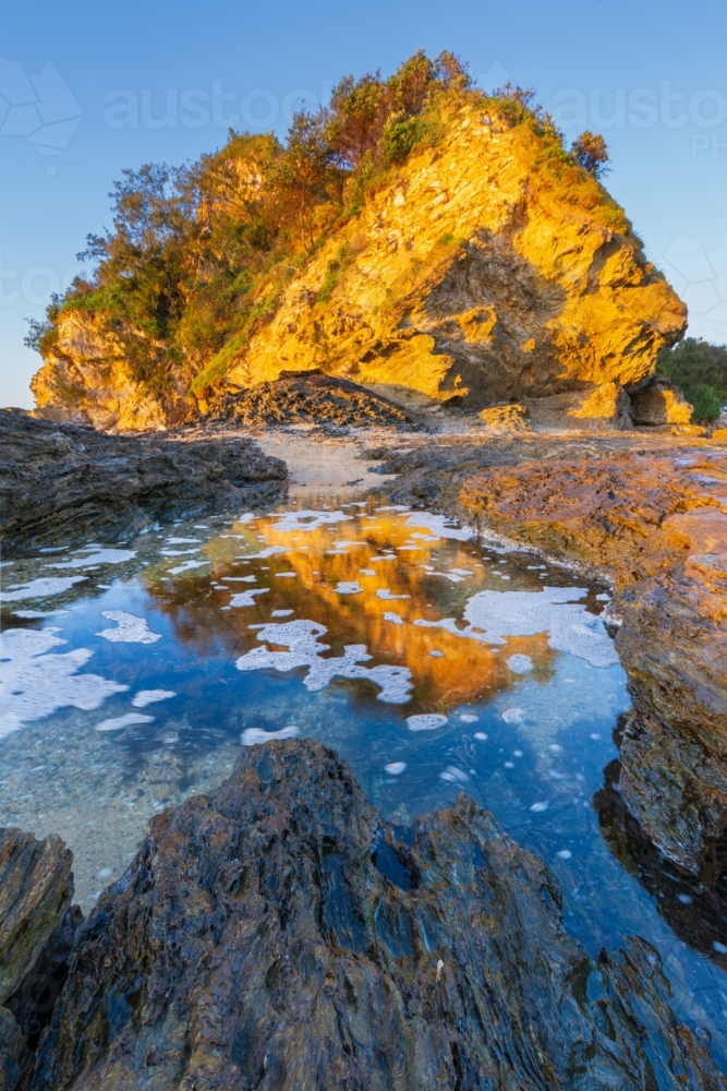 Image of Low angled view of rock formation reflected in a rockpool on a ...