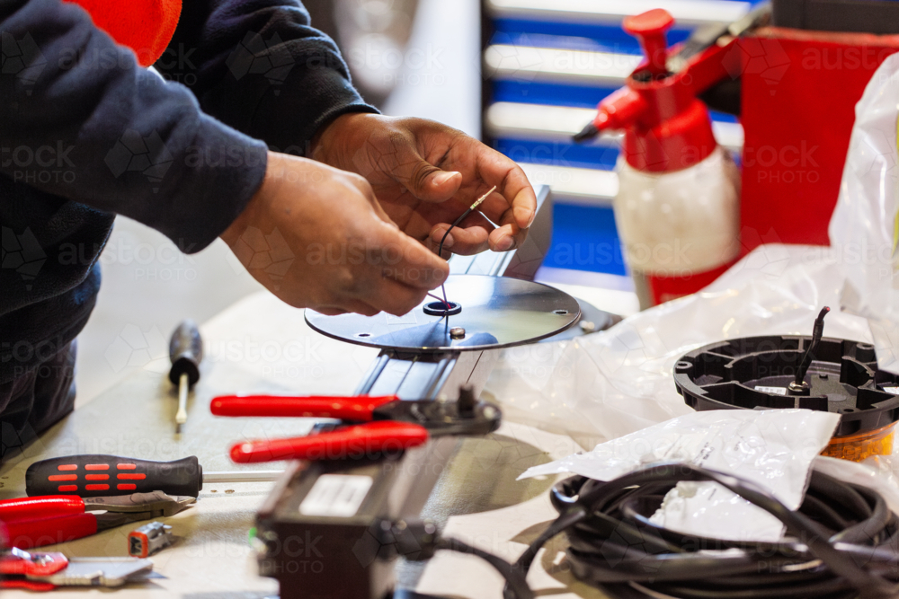 Image of Male technician working on the wiring on circular metal plate ...