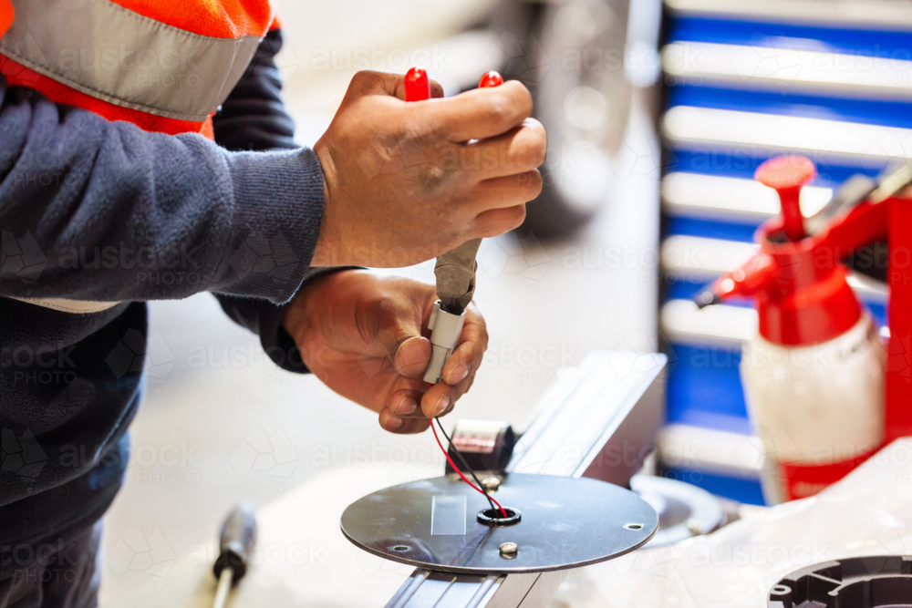 Image of Male technician working on the wiring on circular metal plate ...