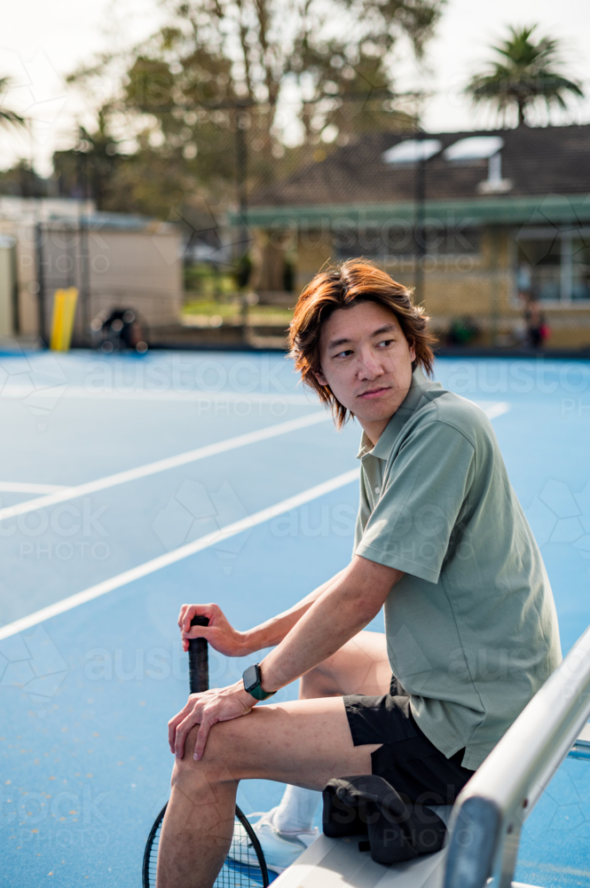 Image of Male tennis player takes a break on the court, enjoying the ...
