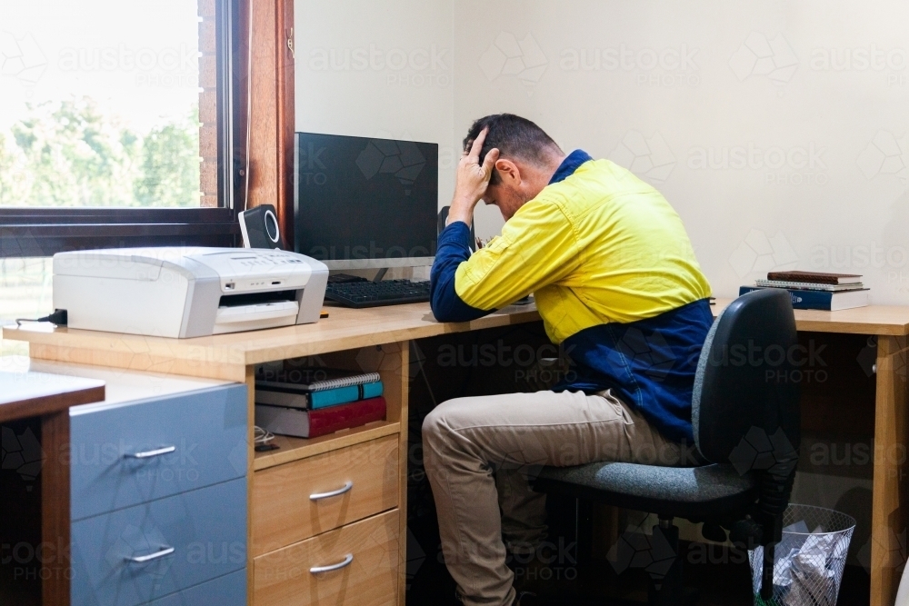 Image of Male tradie at home office desk feeling overwhelmed and ...