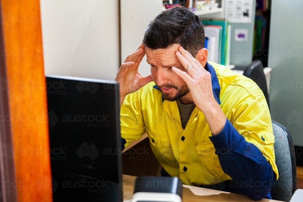 Image of Male tradie at home office desk feeling overwhelmed and ...