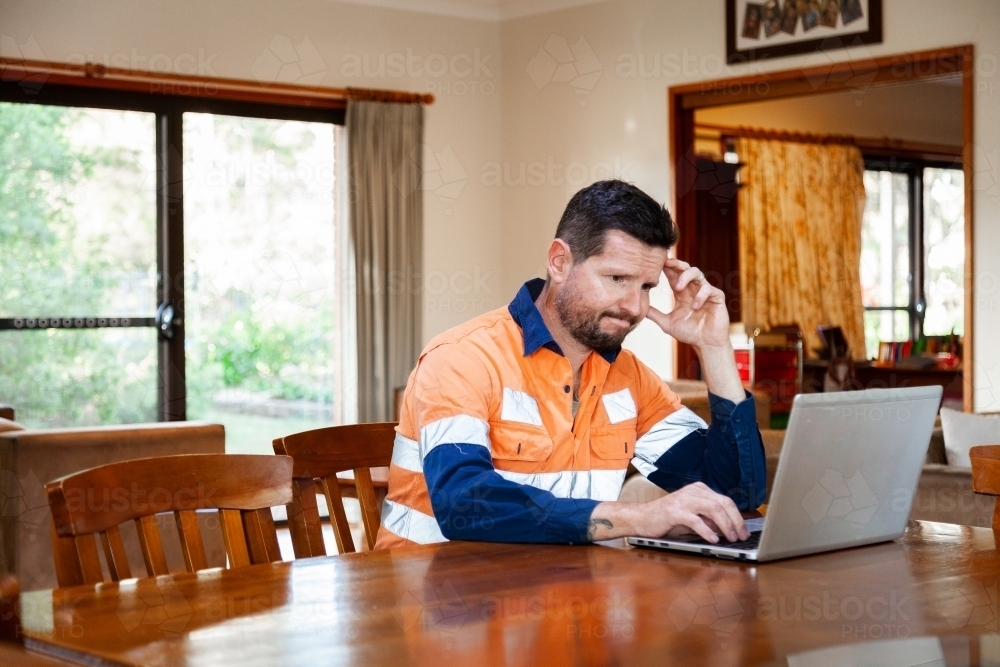 Image of Male tradie in his 30s on laptop feeling overwhelmed and ...