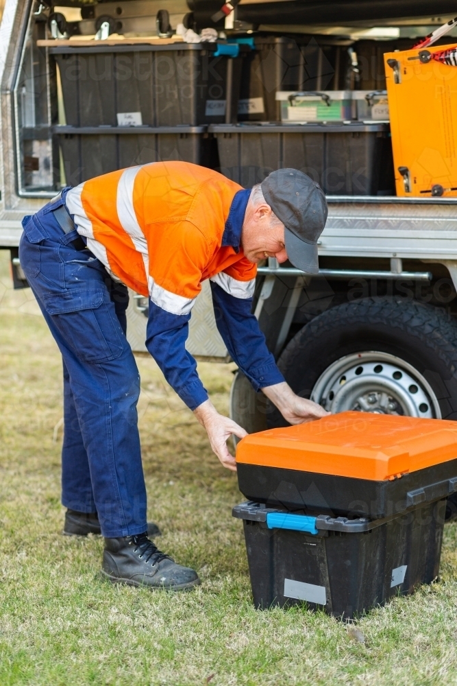 Image of male tradie opening box of tools beside ute - Austockphoto