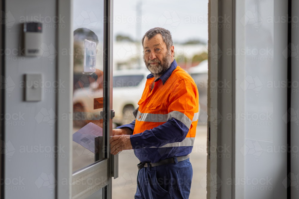 Image of Male worker walking out of the office door. - Austockphoto
