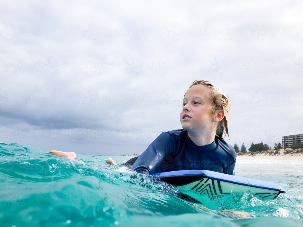 Image of Male youth paddling boogie board in ocean on overcast day ...