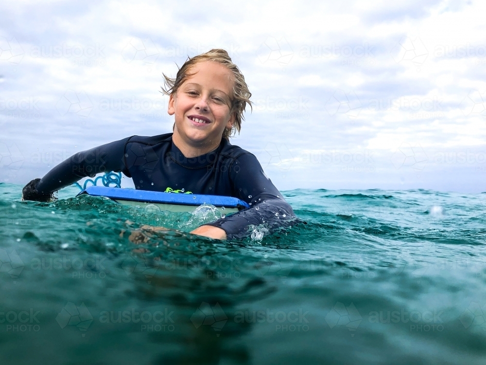 Image of Male youth paddling boogie board in ocean on overcast day ...