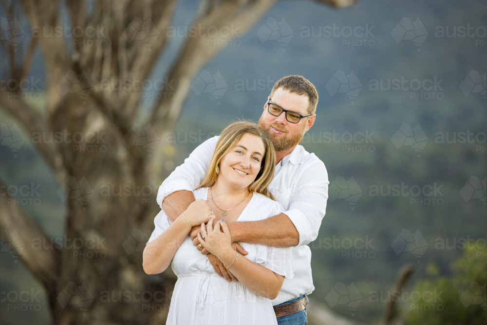 Image of Man and woman embracing in loving hug on hilltop at sunset ...