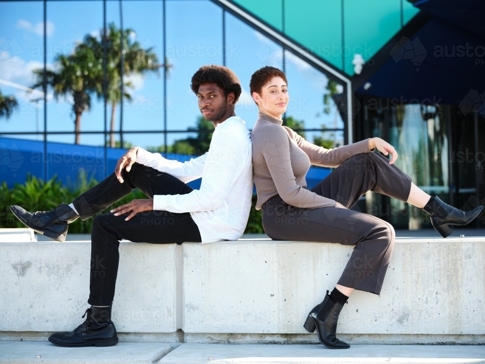 Image of Man and woman sitting back to back on a concrete bench ...