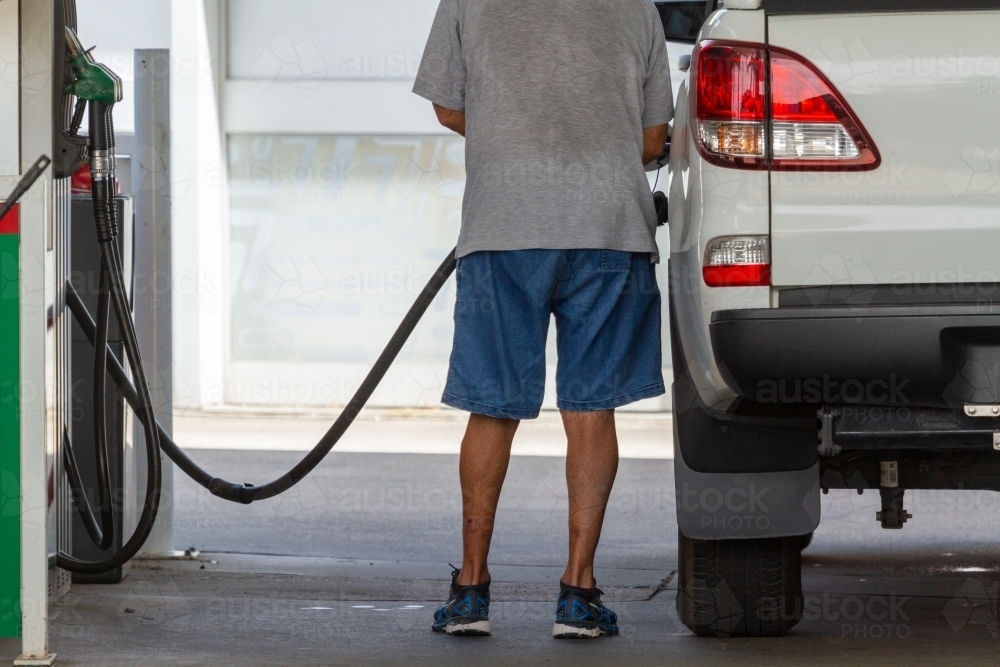 Image of Man at fuel pump filling ute. - Austockphoto