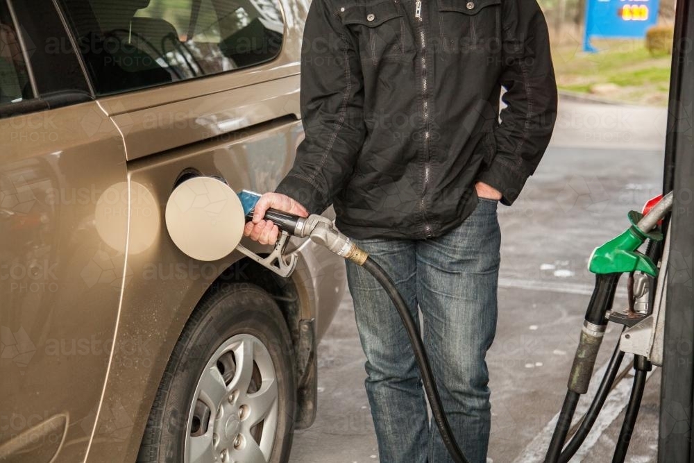 Image of Man at petrol station filling up family car with fuel ...