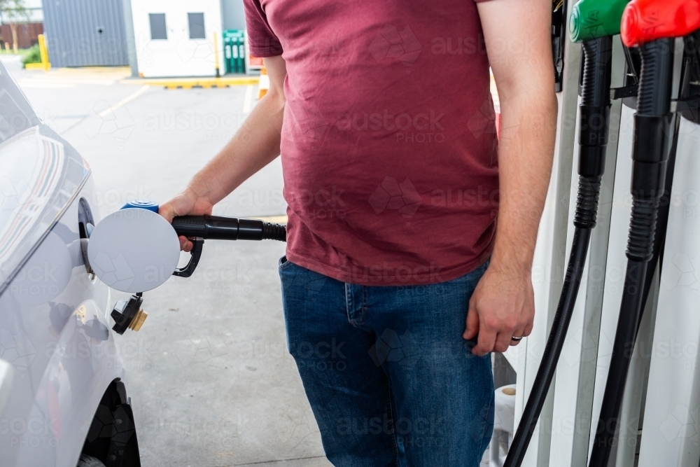 Image of Man at servo filling up car with petrol from pump - Austockphoto