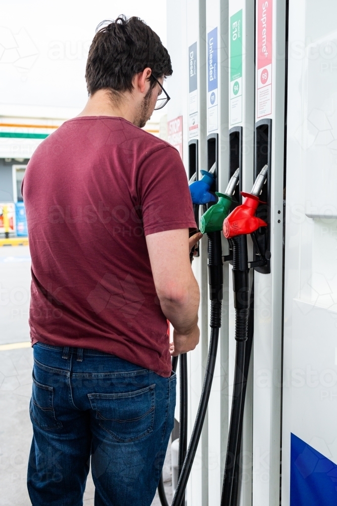 Image of Man at servo filling up car with unleaded petrol from pump ...