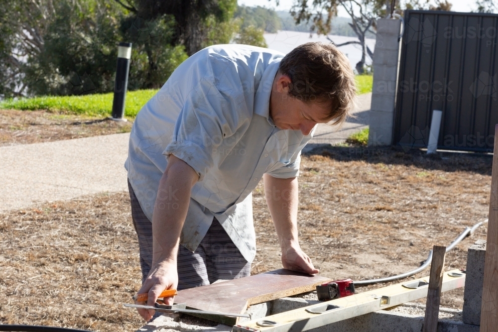 Image of Man bending over diy project outdoors - Austockphoto