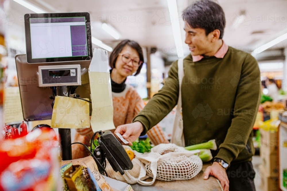 Image of Man buying fresh produce from woman at supermarket counter ...