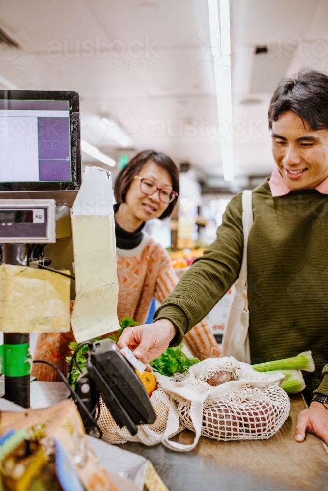 Image of Man buying fresh produce from woman at supermarket counter ...