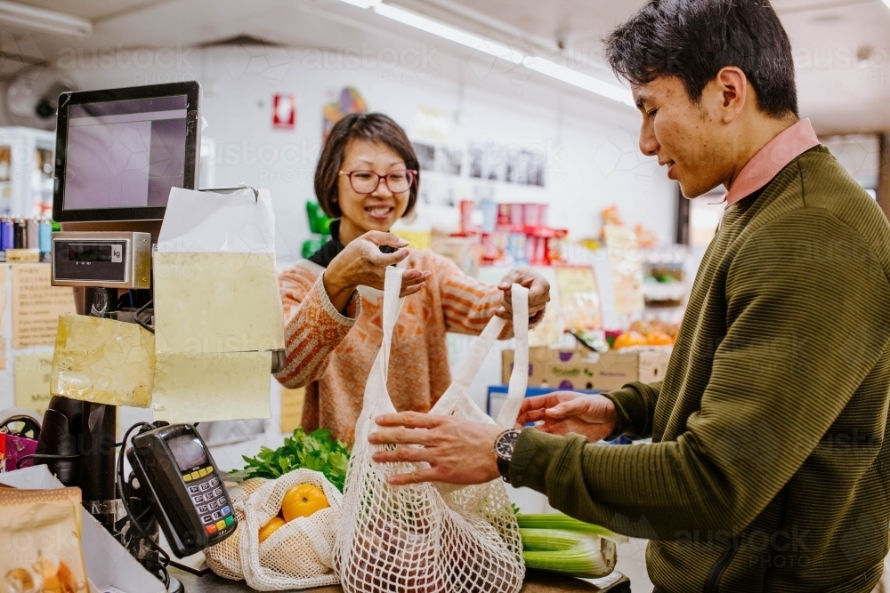 Image of Man buying fresh produce from woman at supermarket counter ...