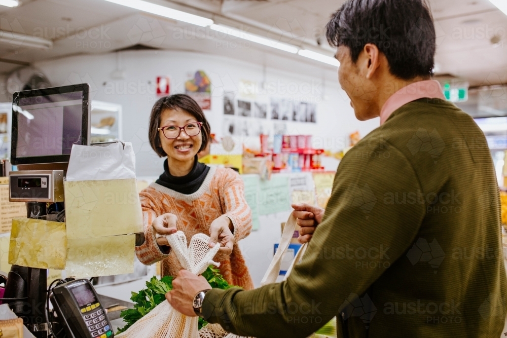 Image of Man buying fresh produce from woman at supermarket counter ...