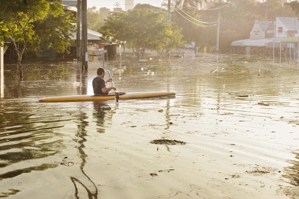 Image of Man canoeing in flood waters - Austockphoto