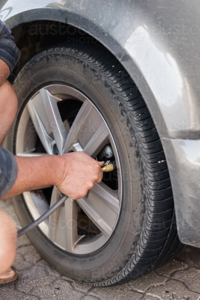 Image of man checking and filling tyres at service station - Austockphoto