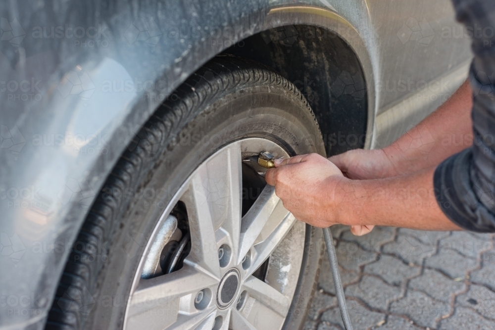 Image of man checking and filling tyres at service station - Austockphoto