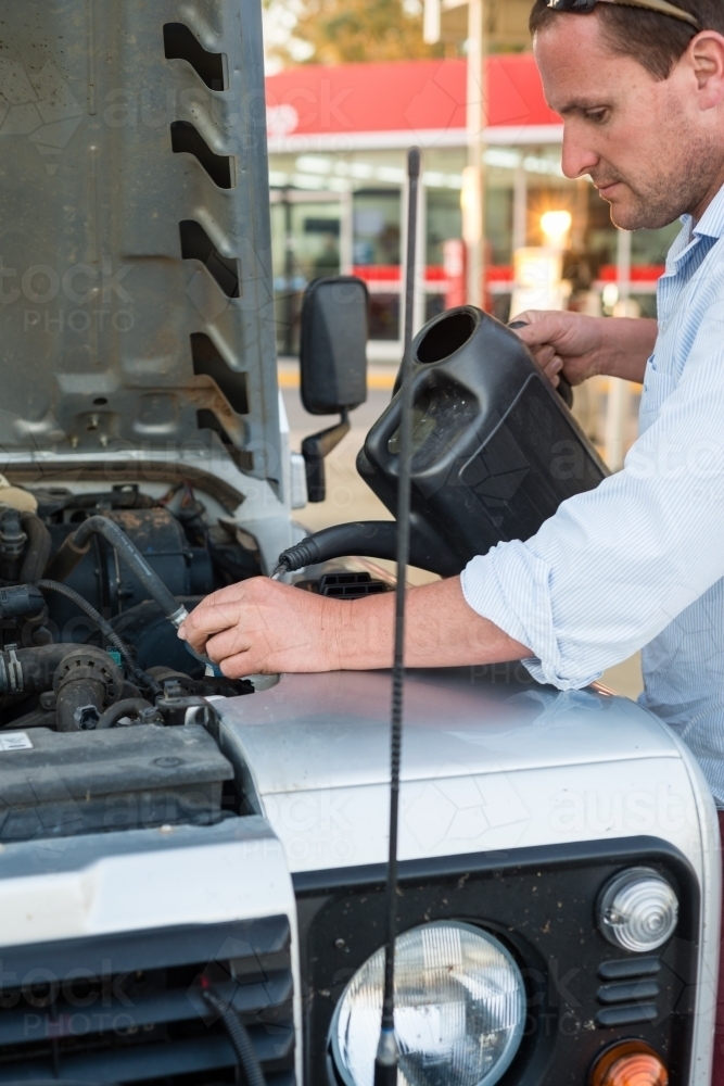 Image of man checking fluids in his car at the fuel station - Austockphoto