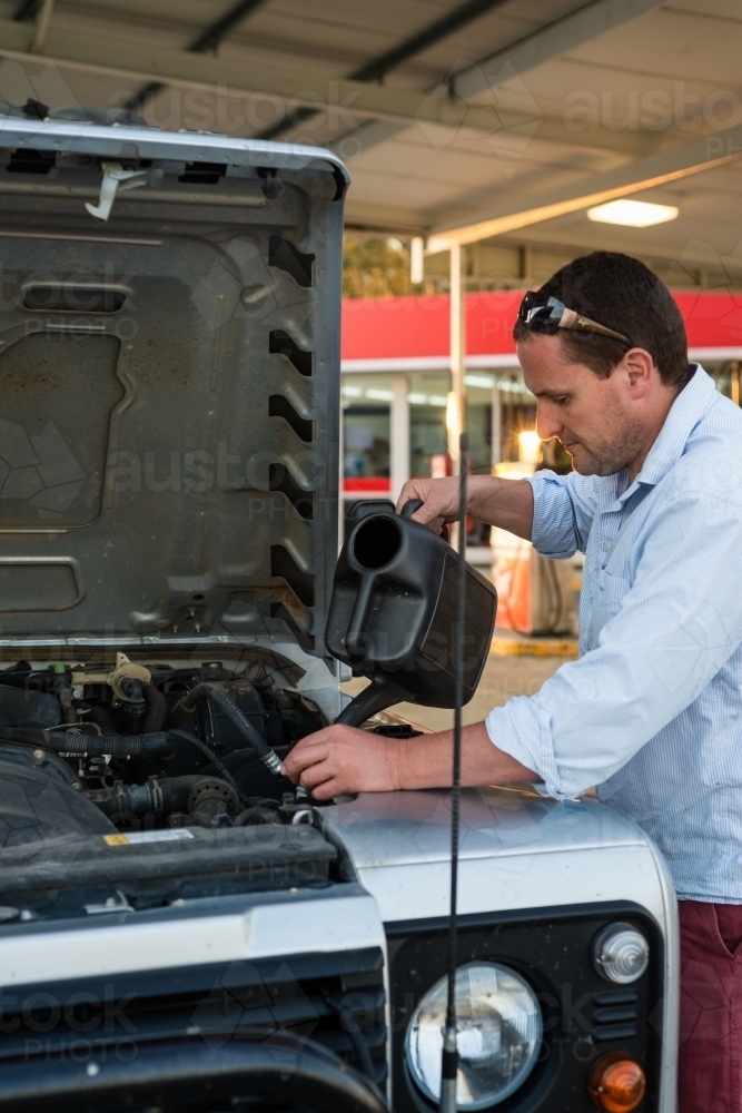 Image of man checking fluids in his car at the fuel station - Austockphoto