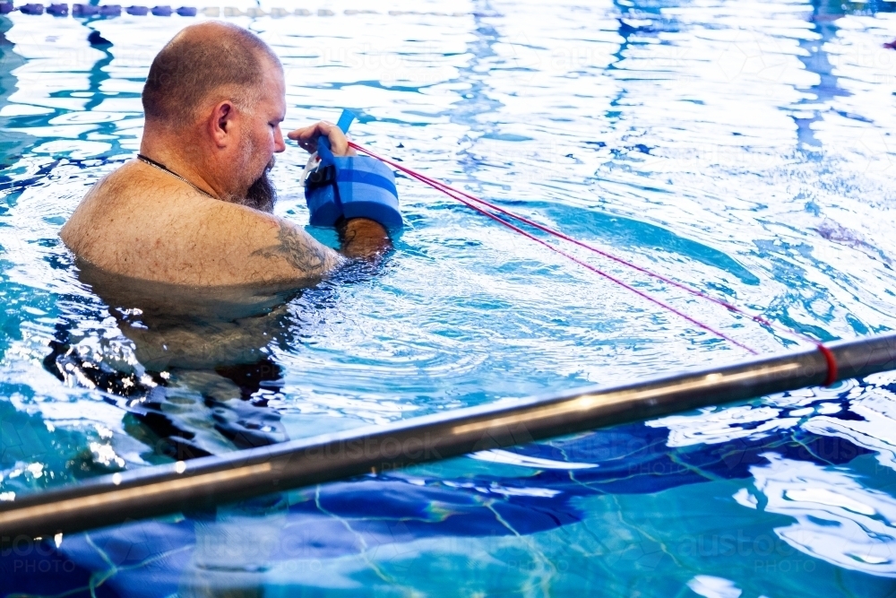 Image of Man doing arm exercises in hydrotherapy class - Austockphoto