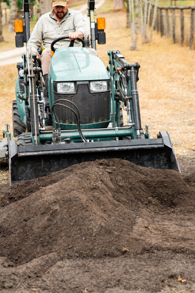 Image of man doing landscaping work on a small tractor - Austockphoto
