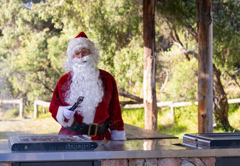 Image of man dressed as santa claus cooking on a public bbq in park ...