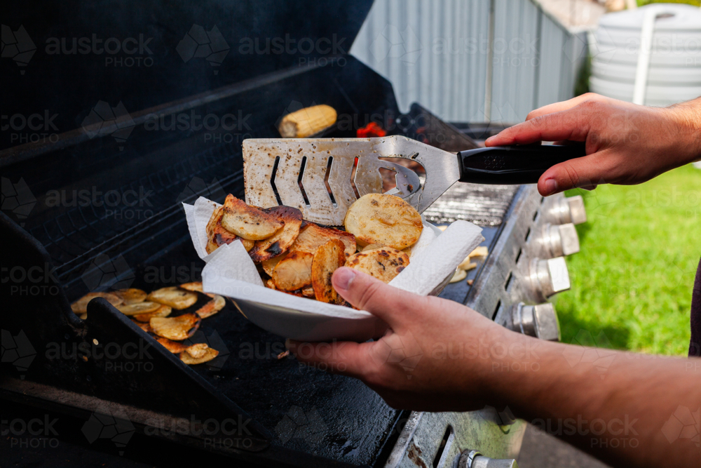 Image of Man finishing cooking home made potato chips on backyard ...