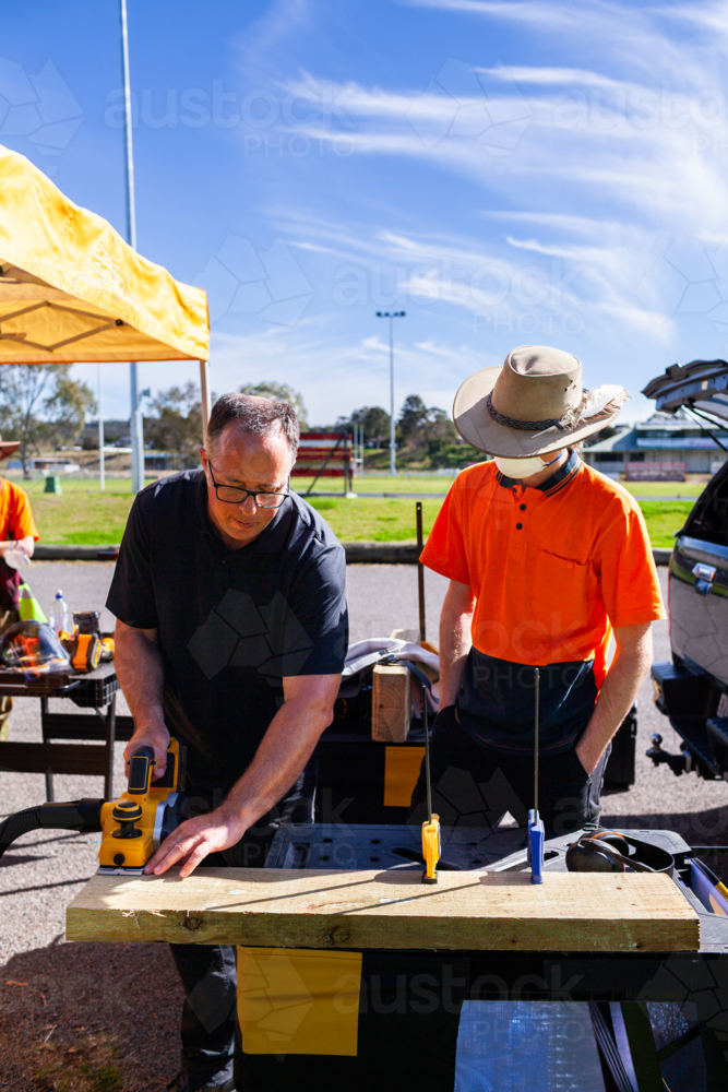 Image of Man giving tool demonstration for trade apprentice - Austockphoto