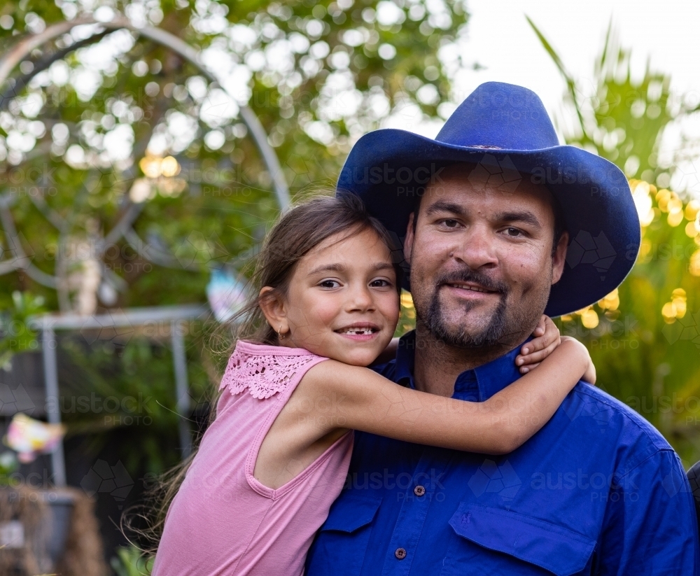 Image of man holding his daughter who is hugging him around the neck ...