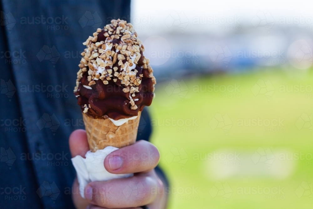 Image of man holding soft serve ice cream with choc nut toping on sunny ...