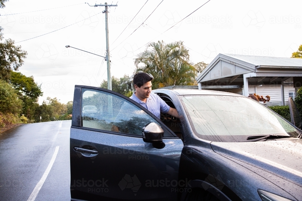Image of man in blue getting inside a black car parked at the side of ...