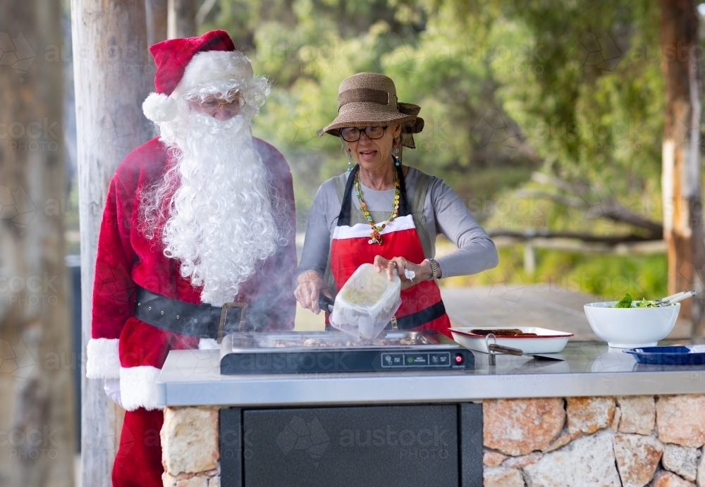 Image of man in santa suit and his wife wearing xmas apron cooking on a ...